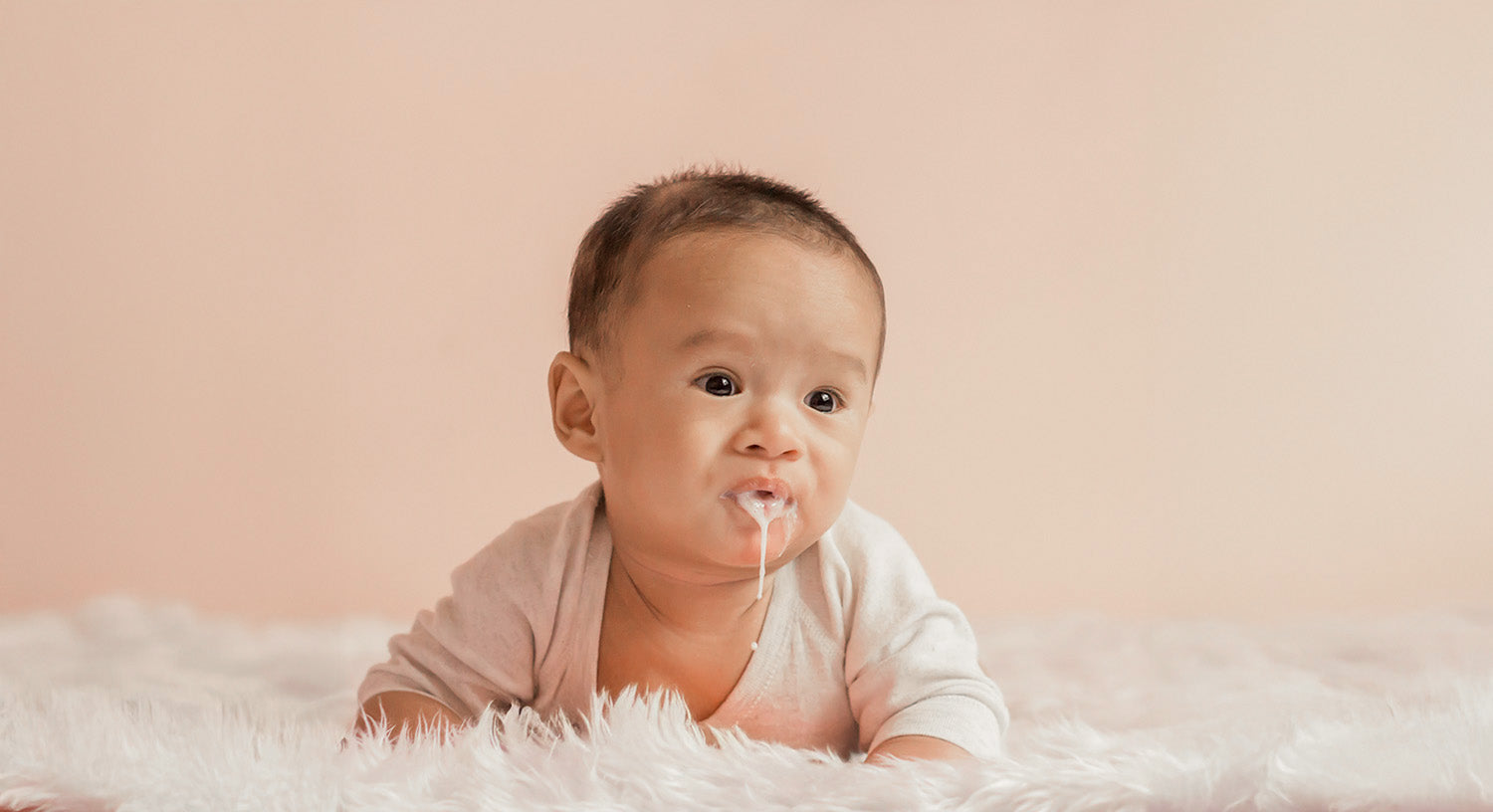 Why do newborn babies spit up or vomit milk after feeding?